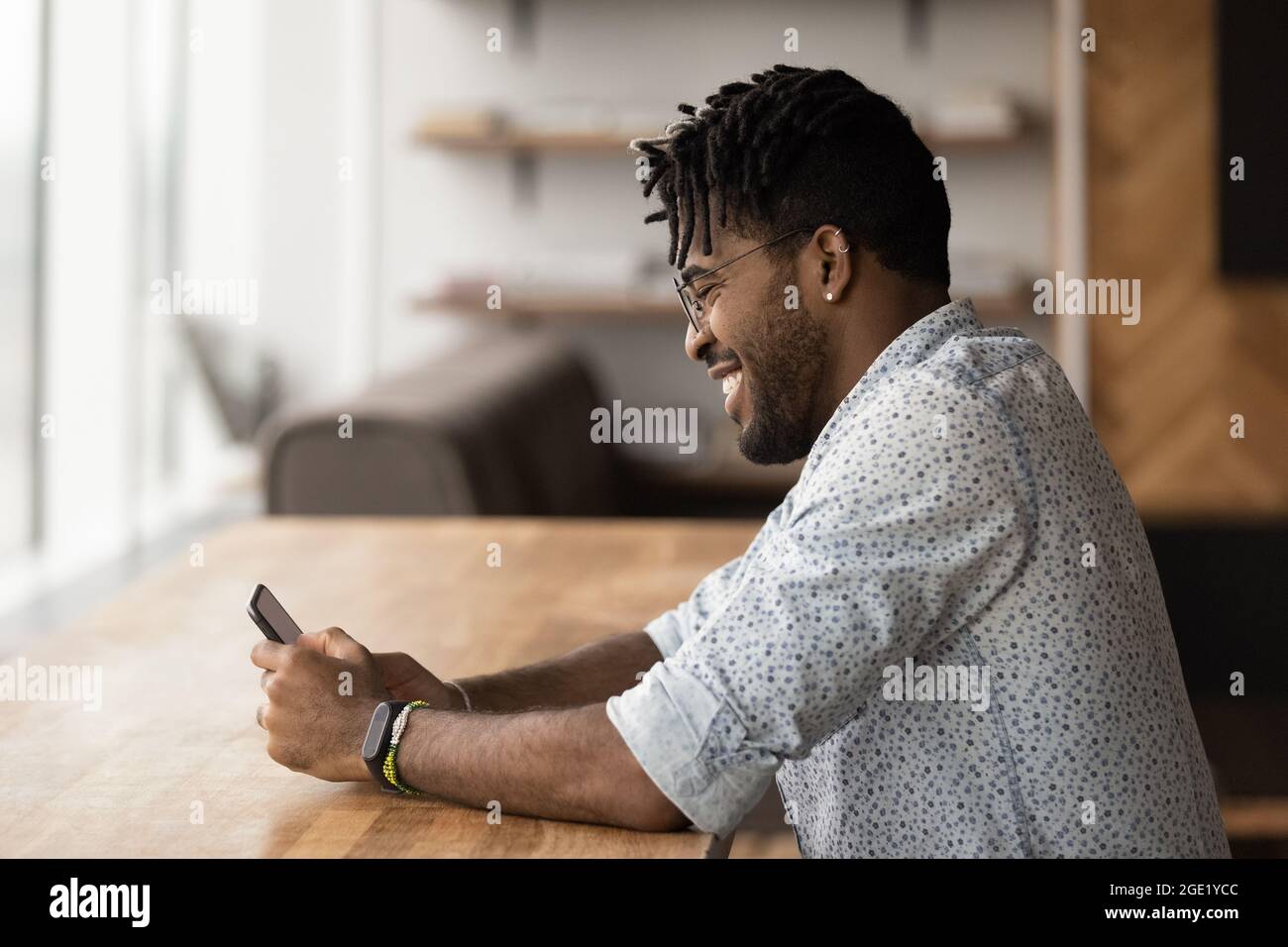 Attractive African man sit at modern office desk with smartphone Stock ...