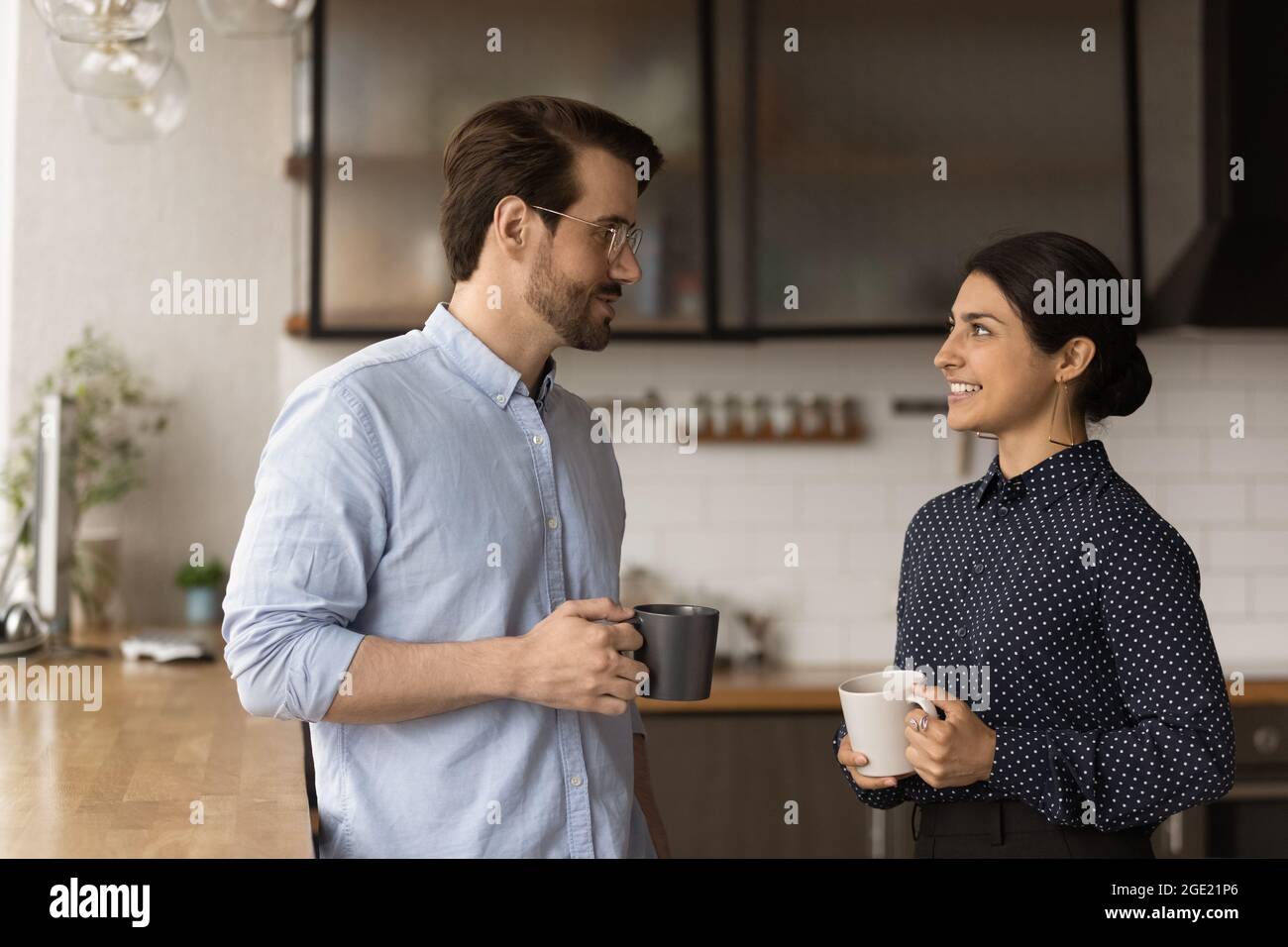 Multiracial colleagues talking during lunch break in office kitchen ...