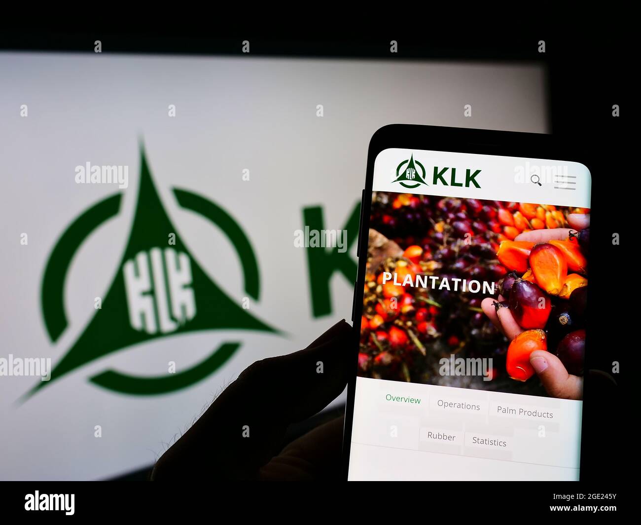 Person holding mobile phone with webpage of Malaysian company Kuala ...