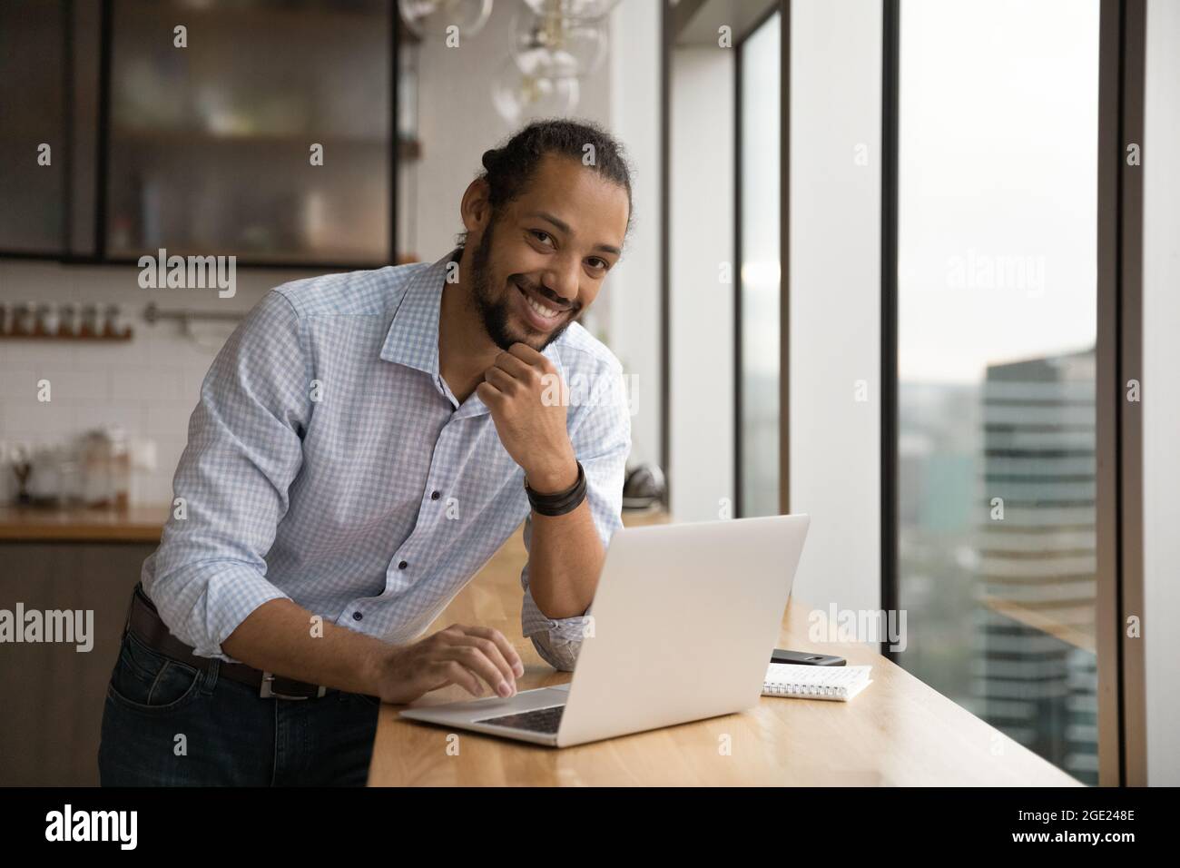African businessman lean at table with computer look at camera Stock ...