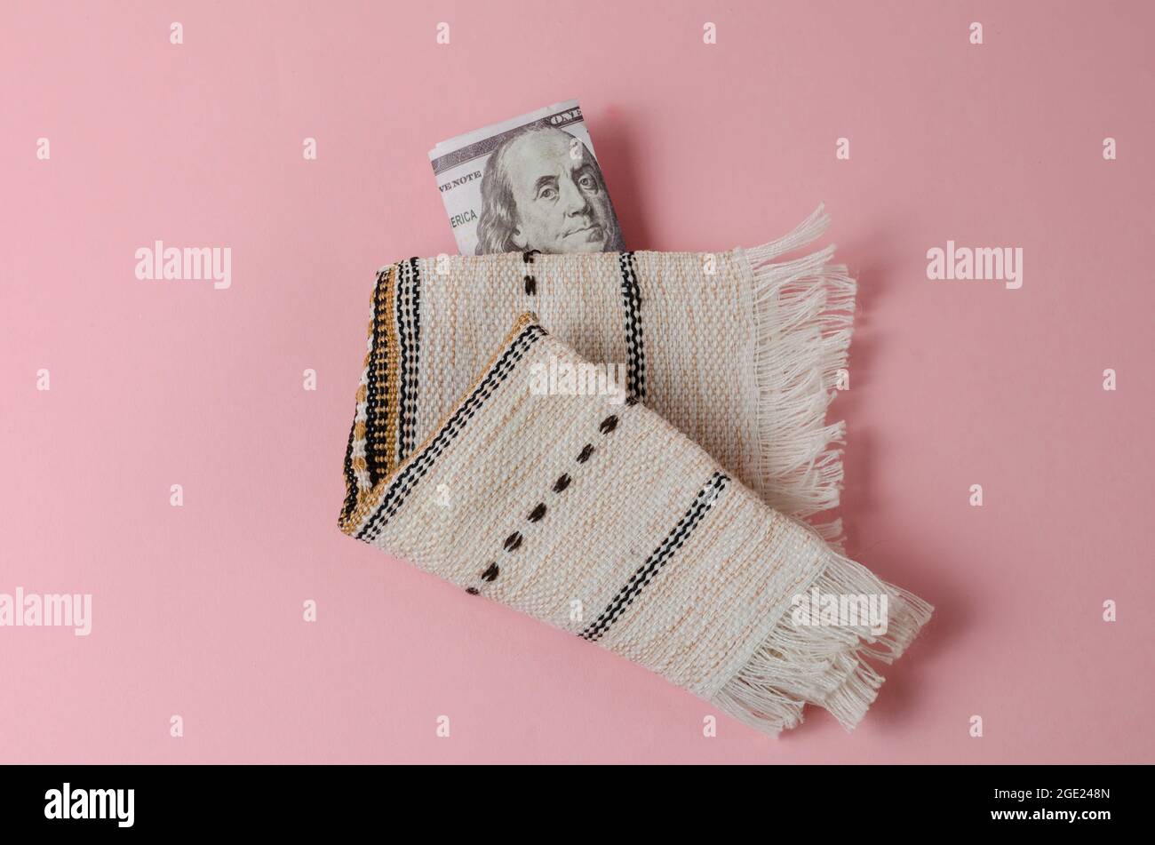 Money and white fringed napkin on pink background. The one hundred ...