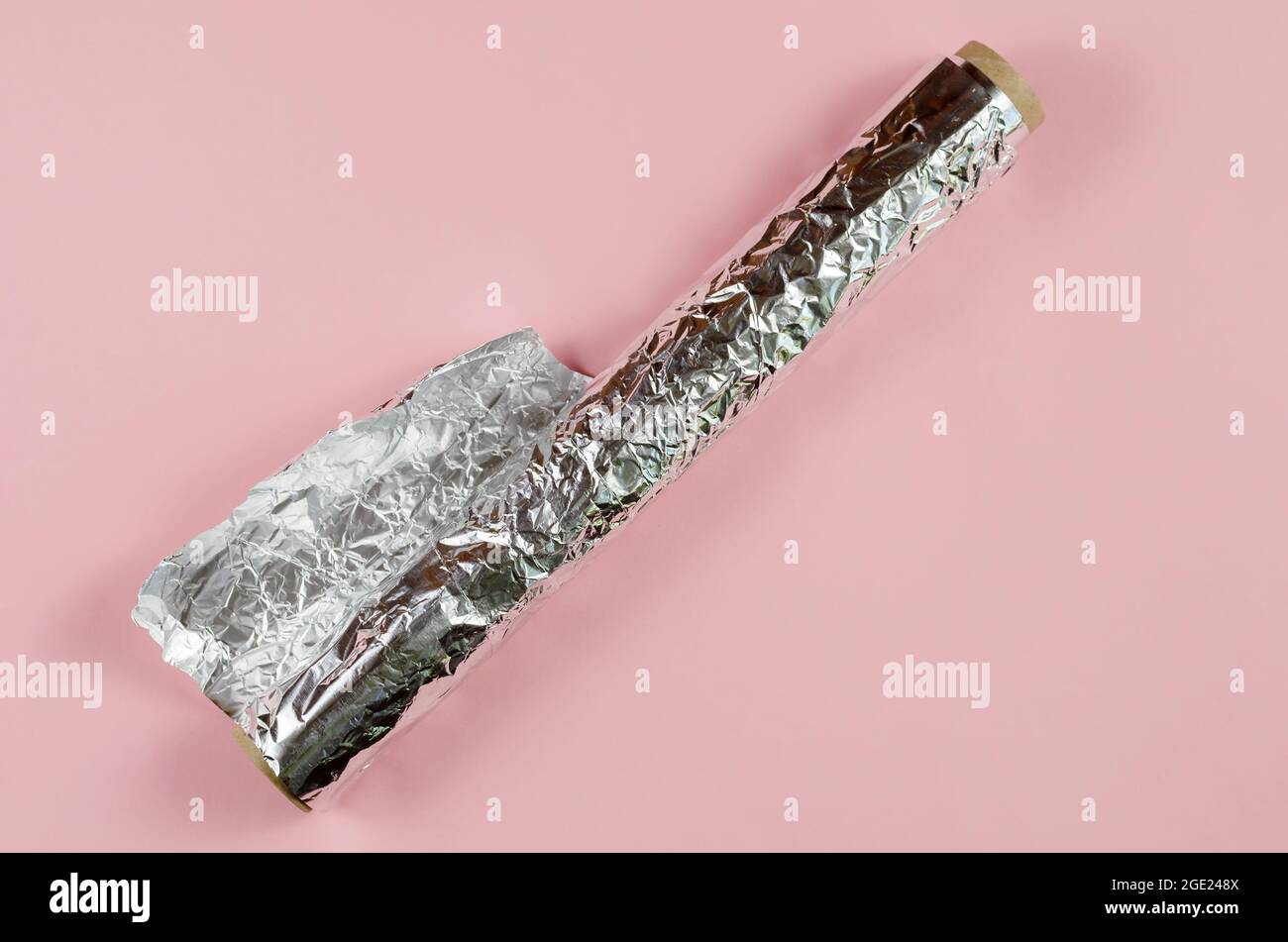 Crumpled foil opposite the pink background. Roll of aluminum foil for ...