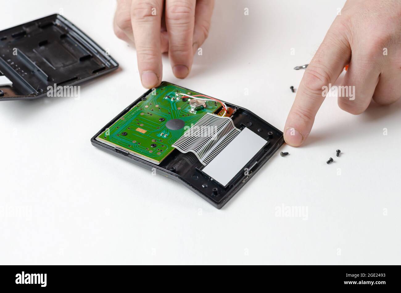Hands, screwdriver, calculator on white background. Man disassembles ...