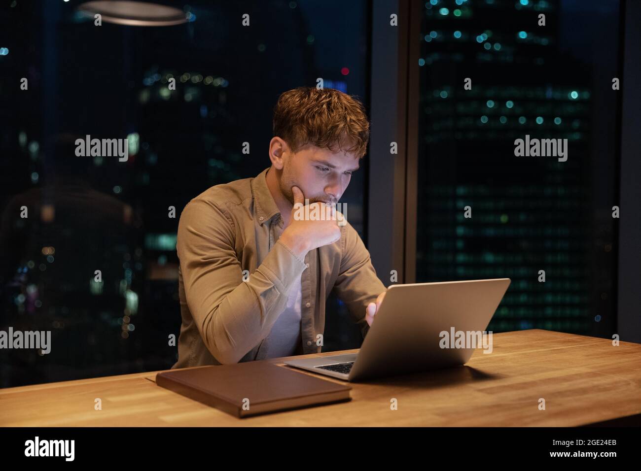 Young employee working on laptop until late in office Stock Photo - Alamy