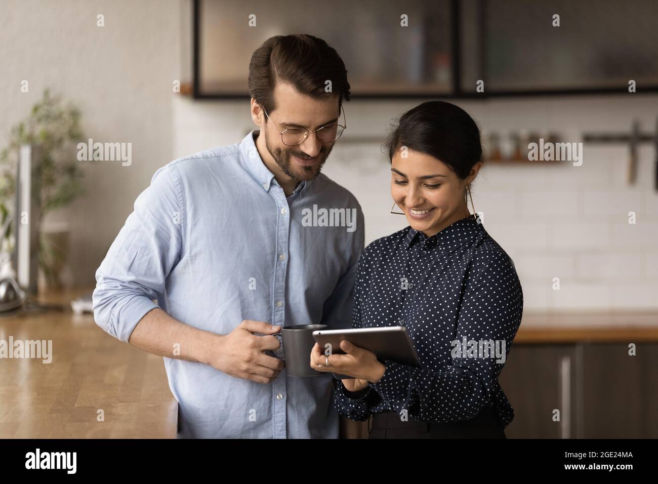 Colleagues standing in kitchen at break discuss project use tablet ...