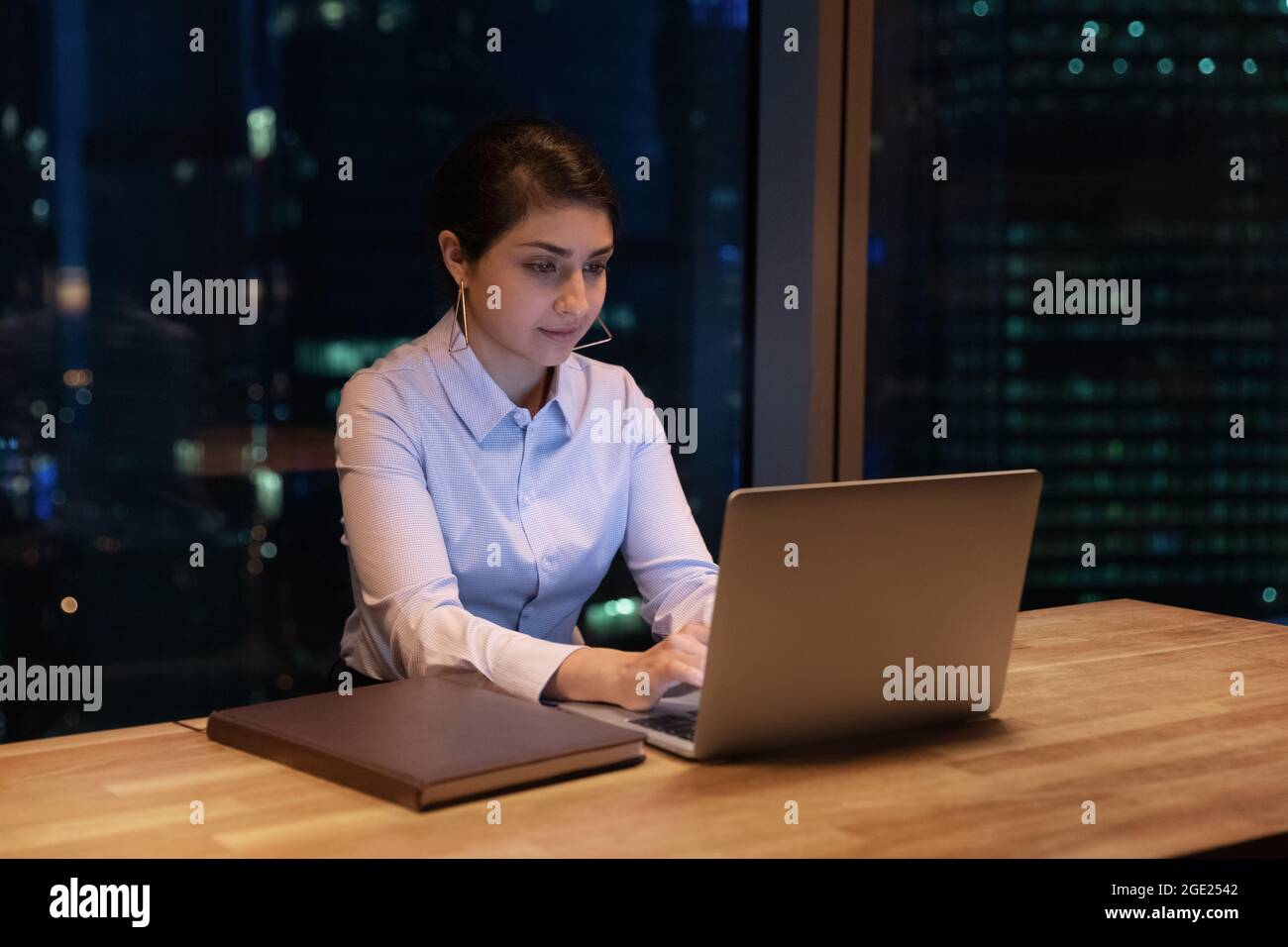 Indian woman texting on computer working until late in office Stock ...