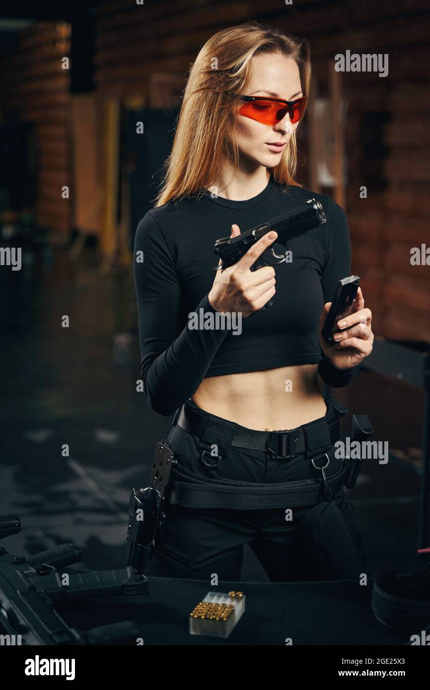 Focused female checking her handgun before a shooting drill Stock Photo ...