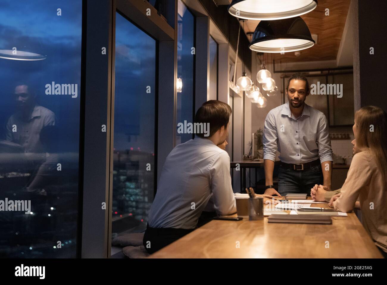 Group of diverse colleagues working until late in modern office Stock ...