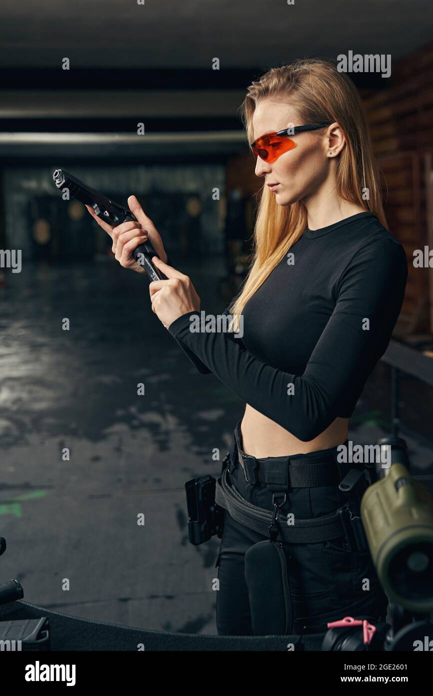 Focused young female shooter concentrated on loading the gun Stock ...
