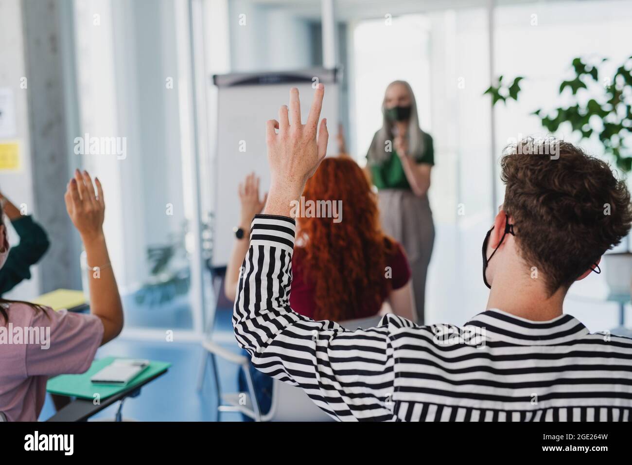 Rear view of university students with teacher studying indoors ...