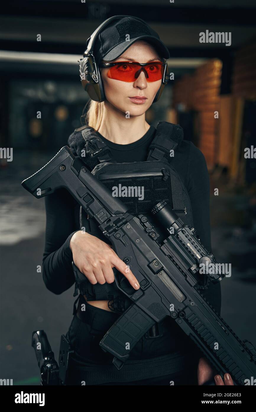 Female shooter with an assault rifle standing indoors Stock Photo - Alamy