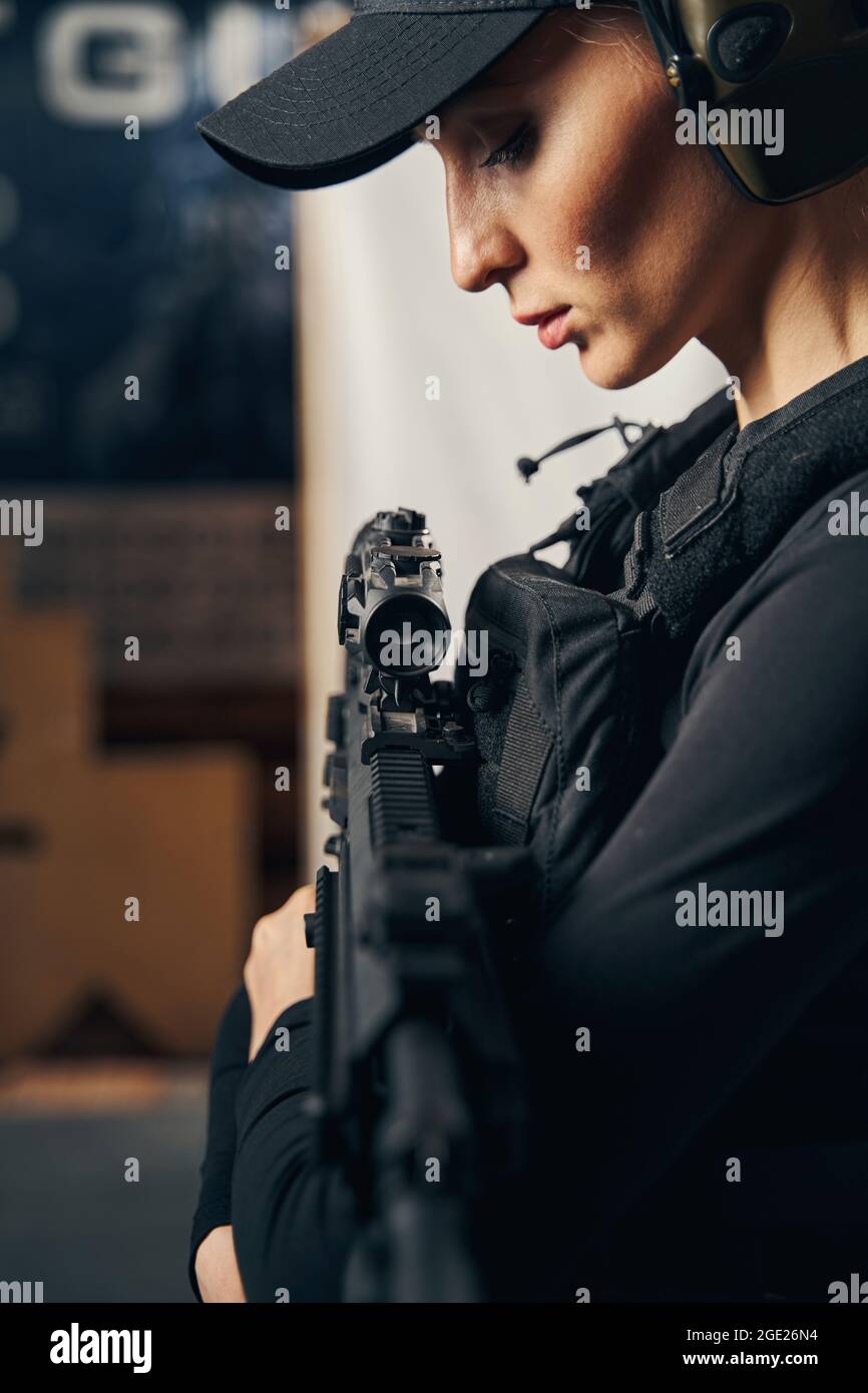 Attractive female shooter pressing the assault rifle to herself Stock ...