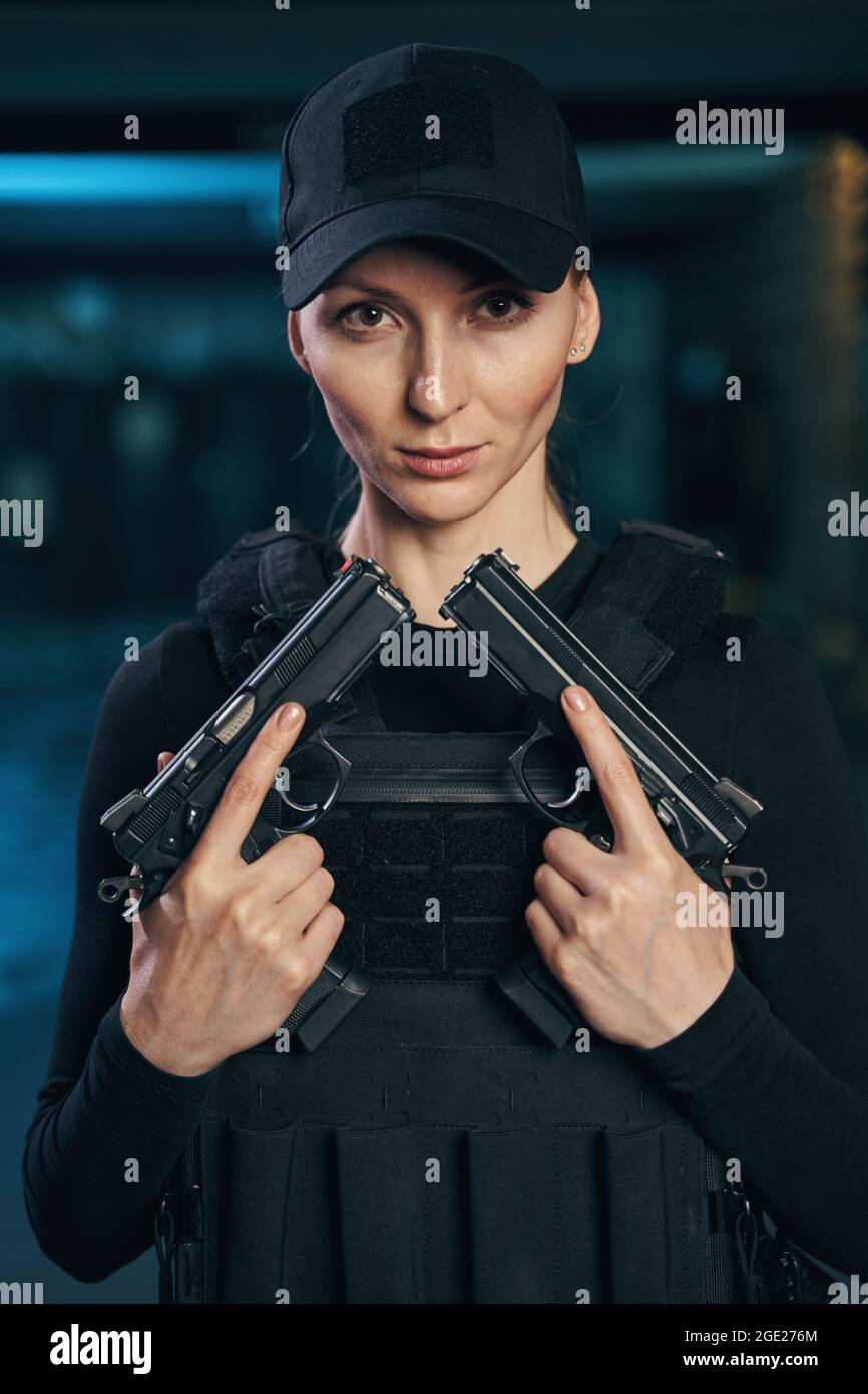 Female shooter with a pair of pistols looking ahead Stock Photo - Alamy