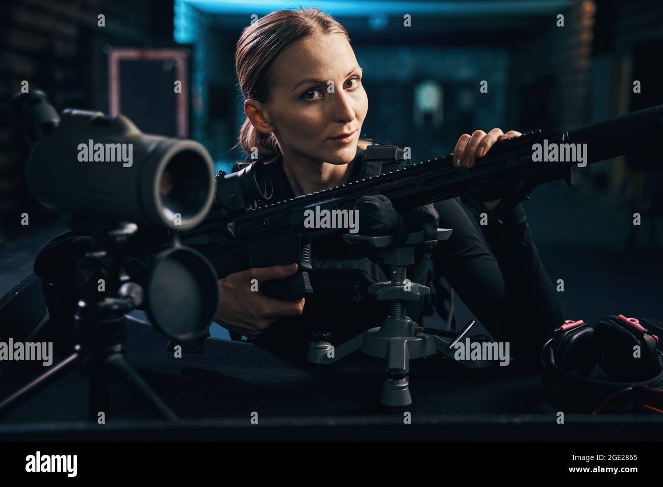 Calm attractive female sniper posing for the camera indoors Stock Photo ...