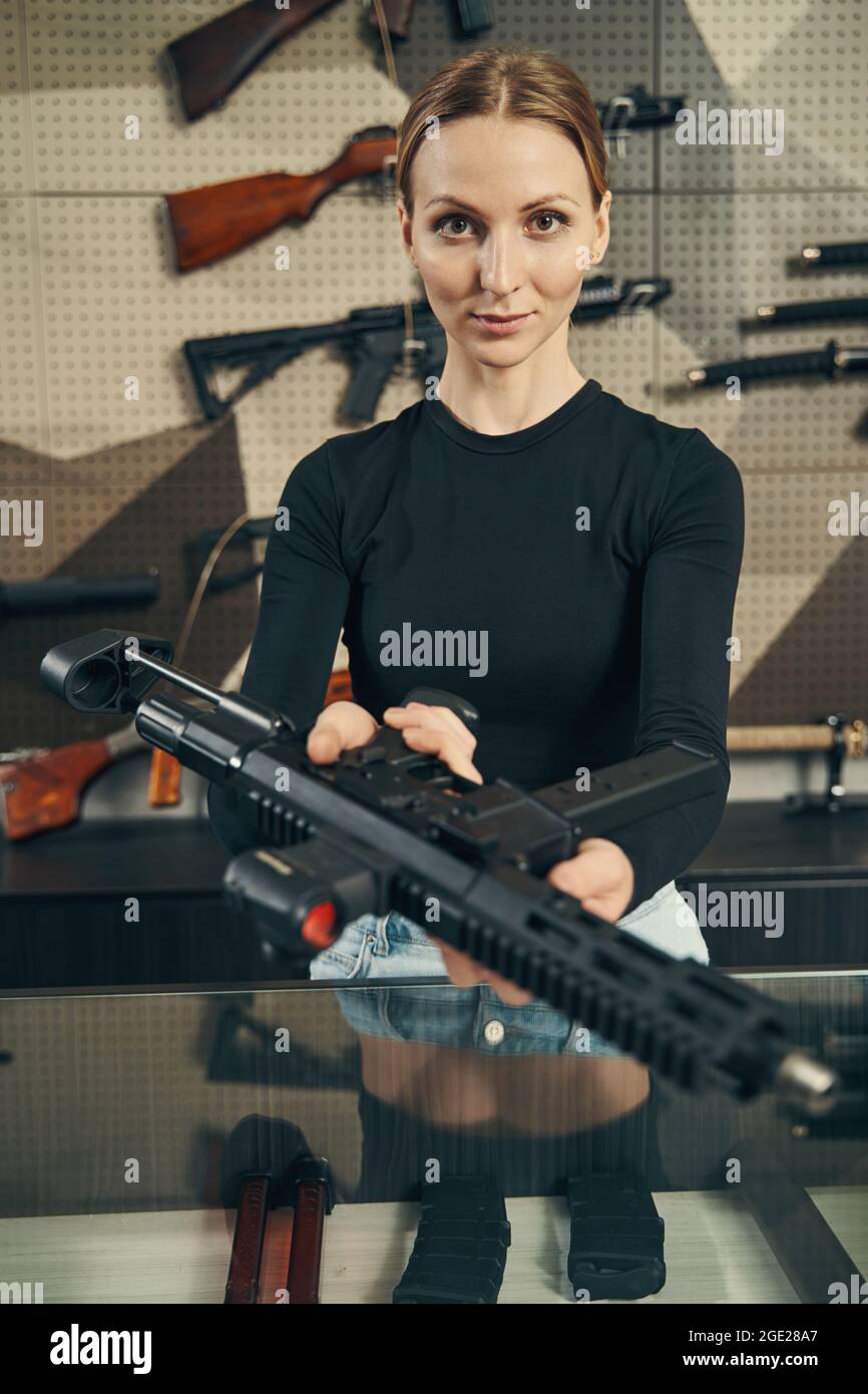 Experienced Caucasian saleswoman demonstrating an unloaded firearm ...
