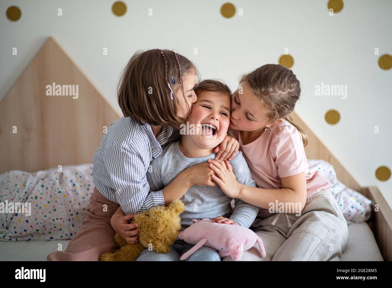 Portrait of three girls sisters indoors at home, kissing Stock Photo ...