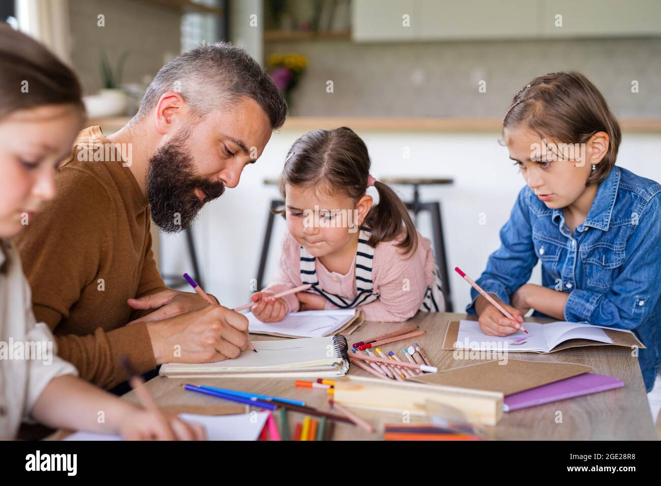 Father With Three Daughters Indoors At Home Drawing Pictures Stock