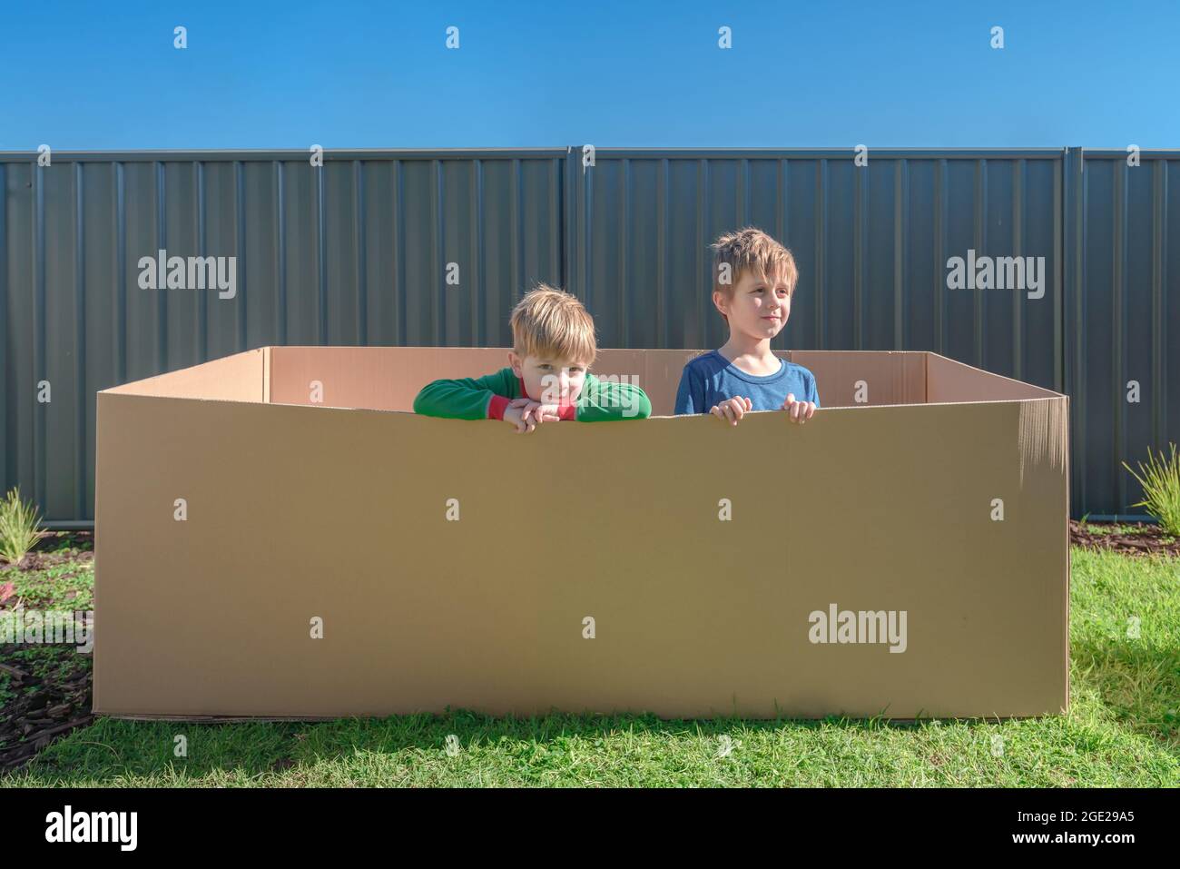 Children sitting inside a big carton box on the backyard Stock Photo ...
