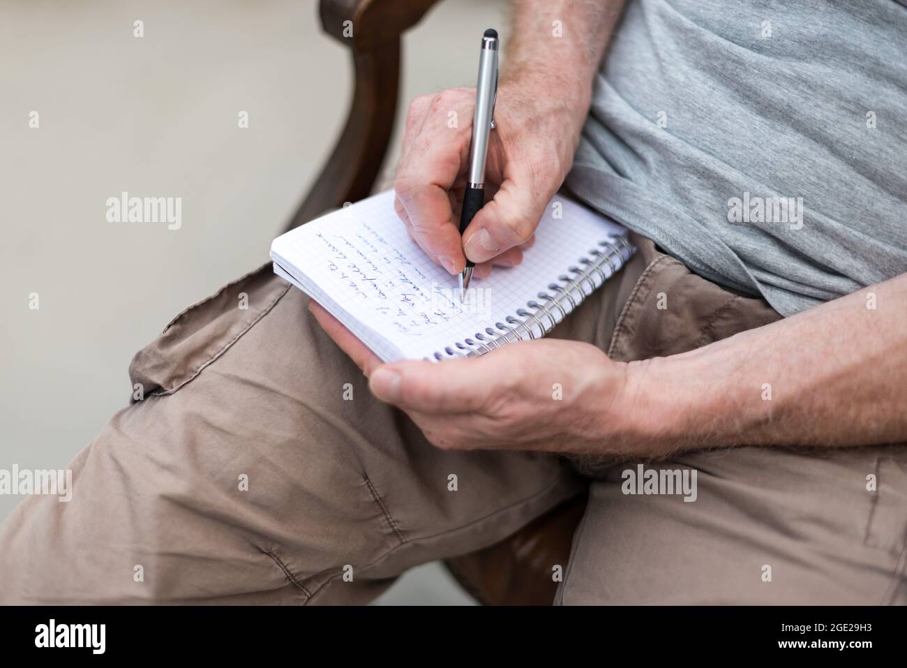 Man sitting outdoor taking notes on a pocket book Stock Photo - Alamy