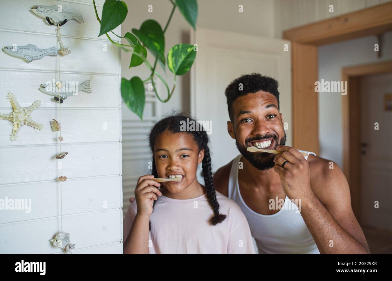 Happy young father with small daughter brushing teeth indoors at home ...