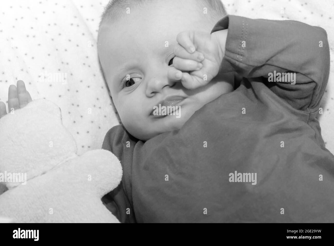 Portrait of tired baby girl lying in her crib, black and white Stock ...