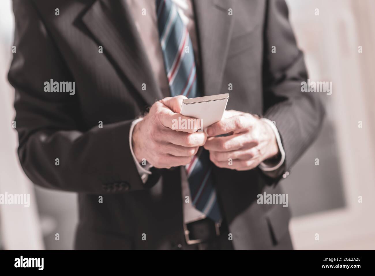 Standing businessman using mobile phone Stock Photo - Alamy