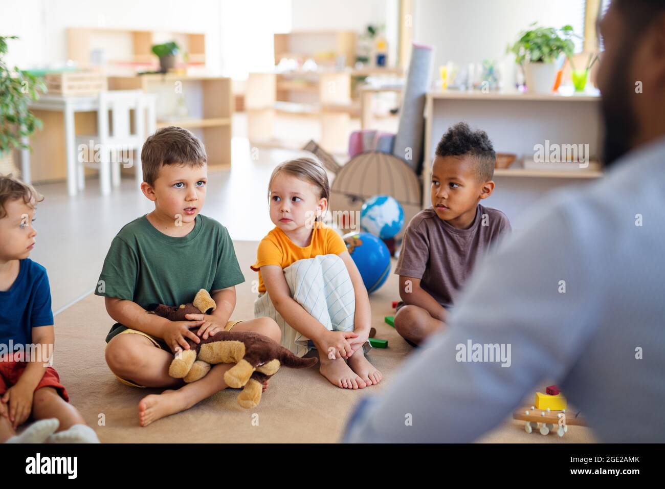 Group of small nursery school children sitting on floor indoors in ...
