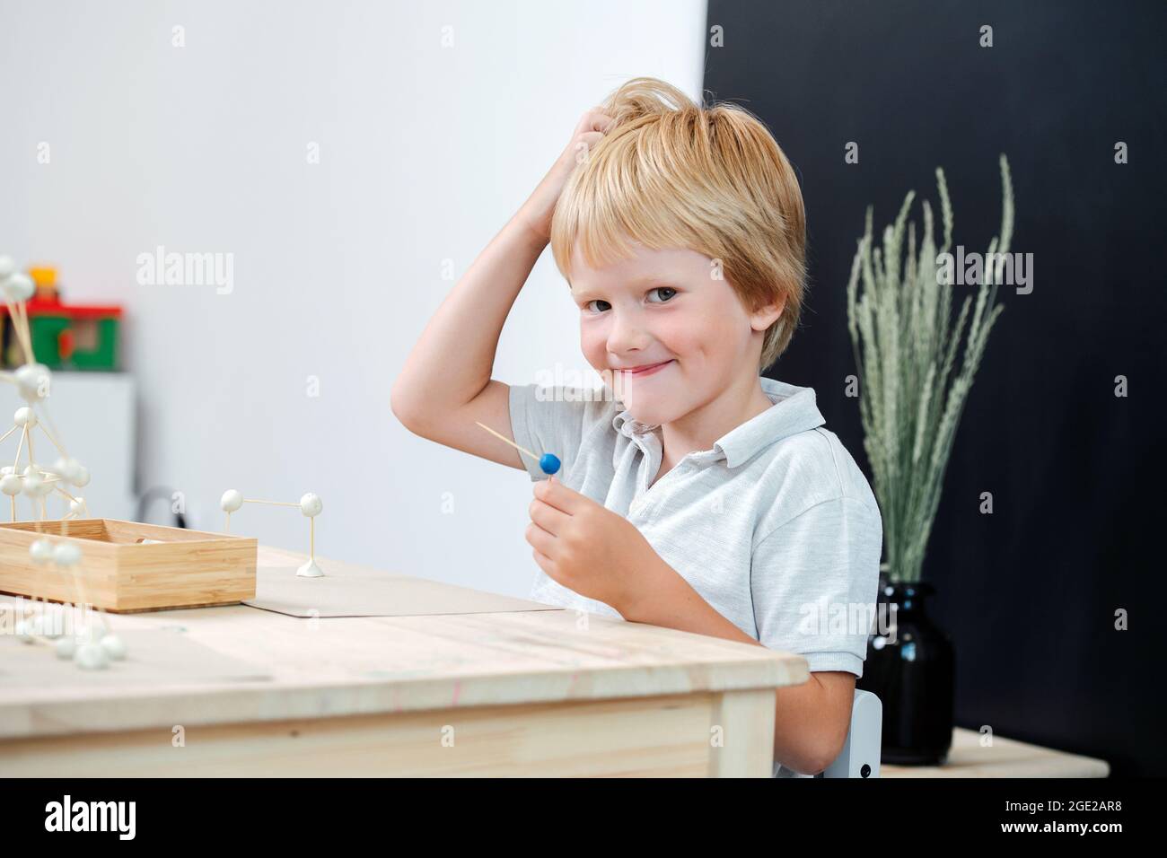 Good looking little boy is busy building shapes from plasticine and ...