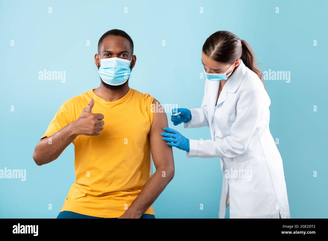 Get vaccinated. Young black guy in face mask showing thumbs up during ...