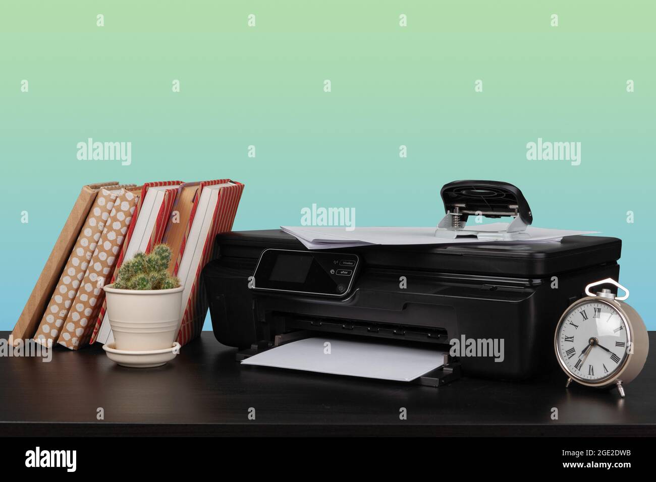 Home laser printer on desk against green background Stock Photo - Alamy