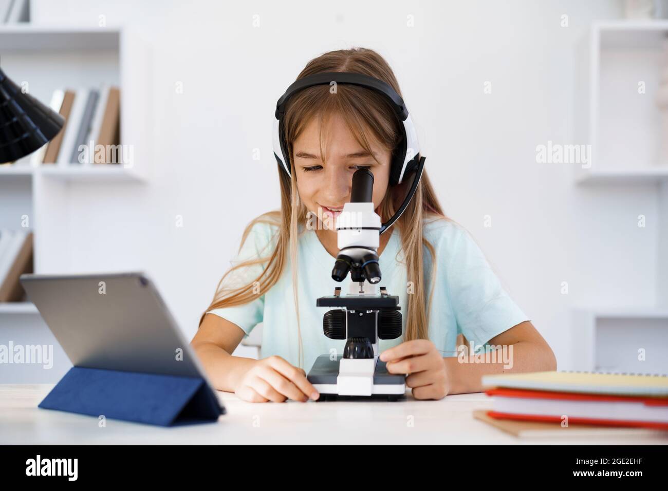 Young girl using microscope during online lesson education at home ...