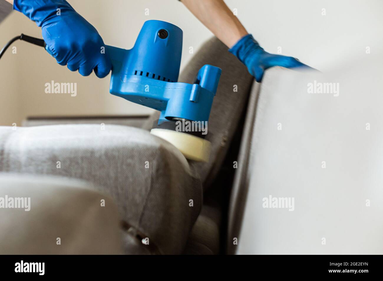 Dry cleaner's man employee removing dirt from furniture in flat ...