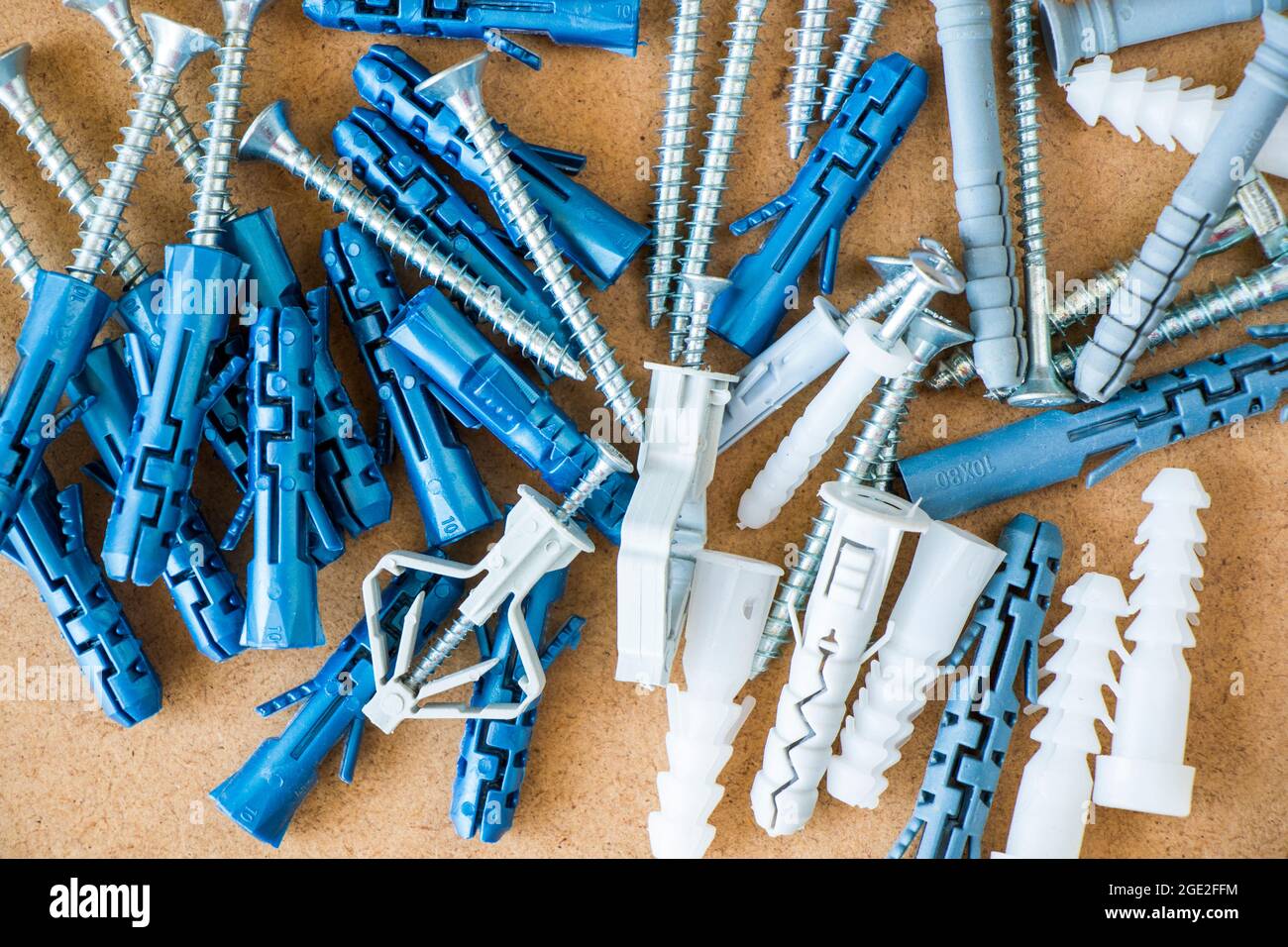 Large group of different wall plugs and screws on the brown background ...