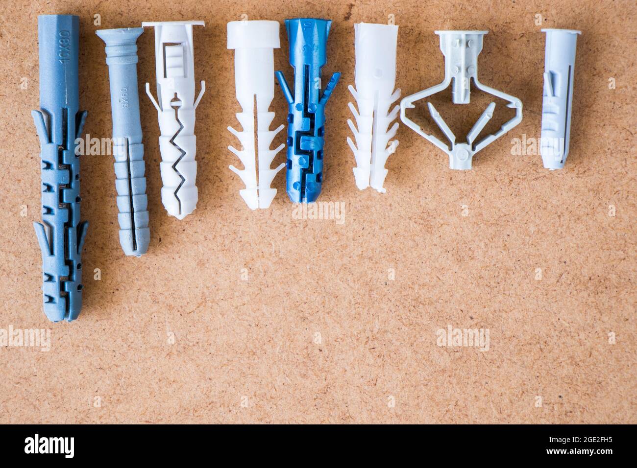 Large group of different plastic wall plugs on the brown background ...