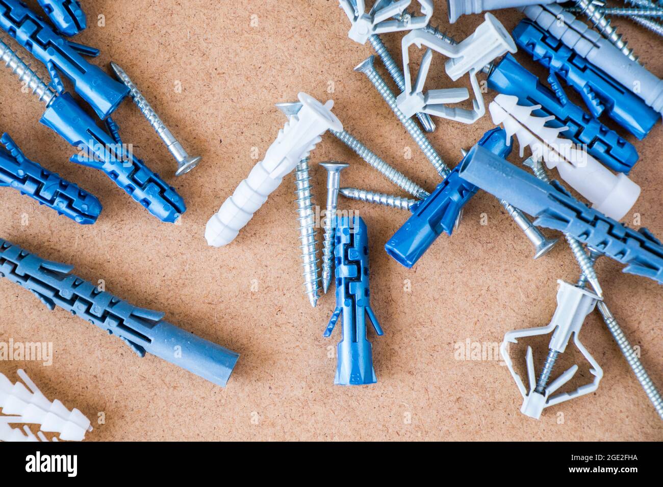 Large group of different wall plugs and screws on the brown background ...