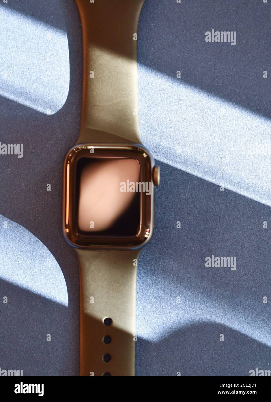 Overhead of a smart watch in sunlight and shadow on blue background ...