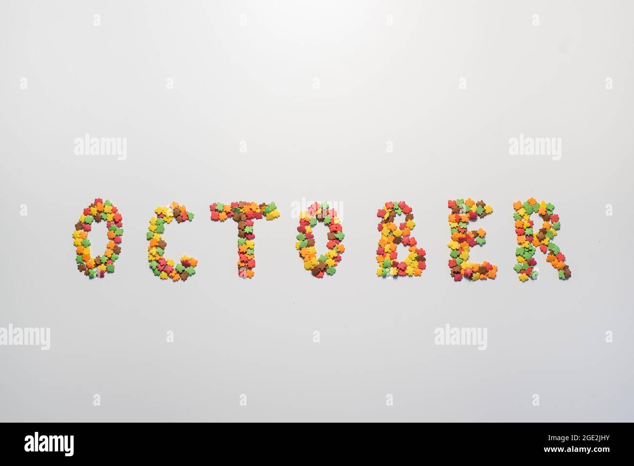 October inscription on a white background. Confectionery sprinkles in ...
