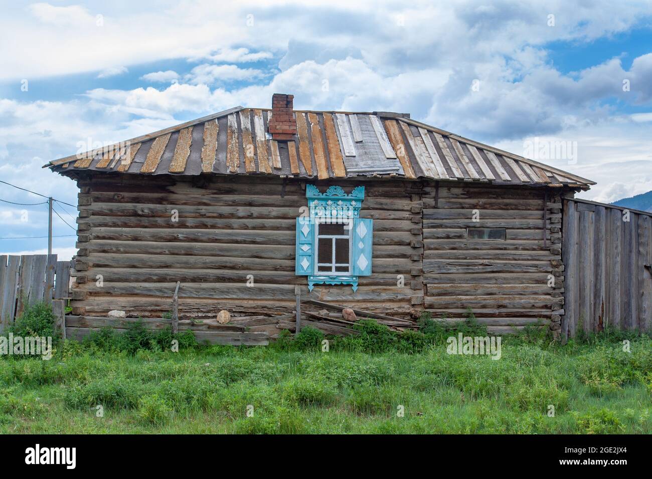 Old Russian log house with window and carved shutters. Chimney on roof ...