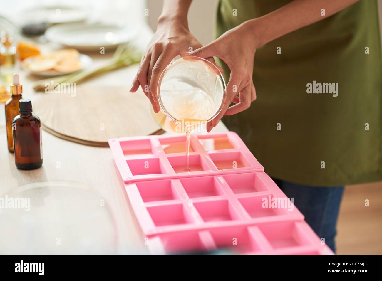 Close-up image of woman pouring melted soap with essential oils into ...