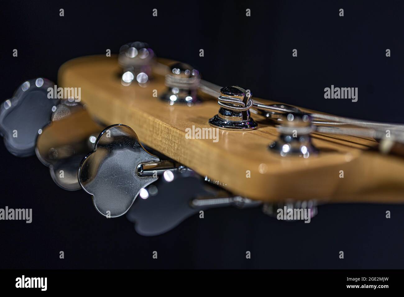 Detail of a tuning post on the wooden headstock of an electric bass ...