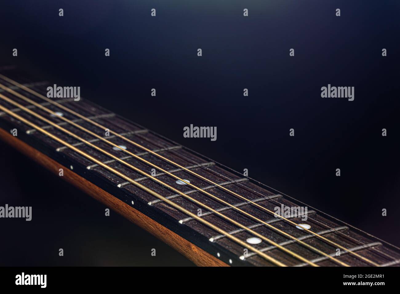 Part of an acoustic guitar, guitar fretboard with strings on a black ...