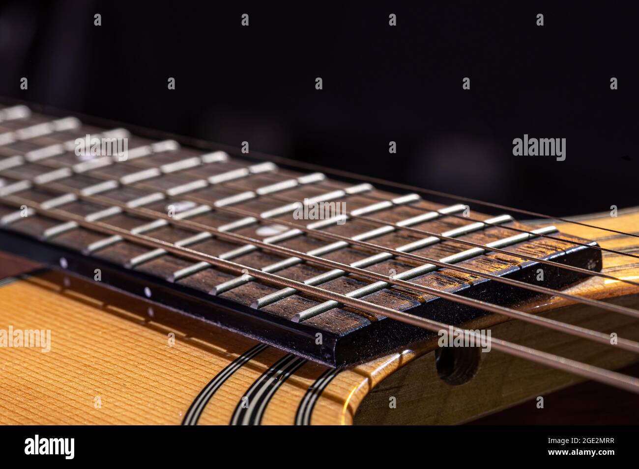 Part of an acoustic guitar, guitar fretboard with strings on a black ...