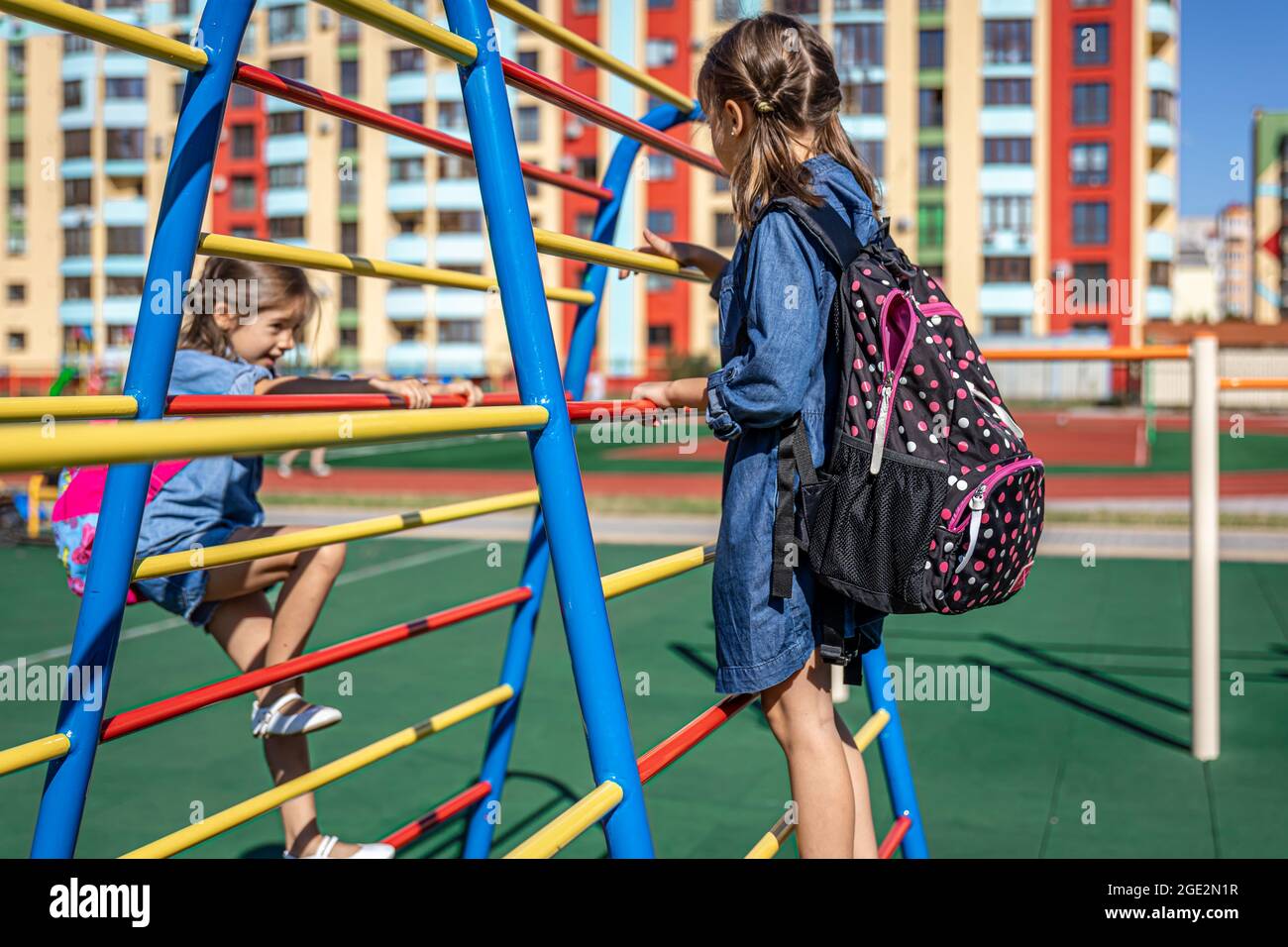 Two little girls, elementary school students, play on the playground ...