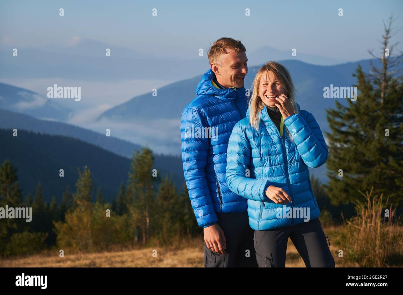 Couple of hikers sincerely laughing while resting in the mountains ...