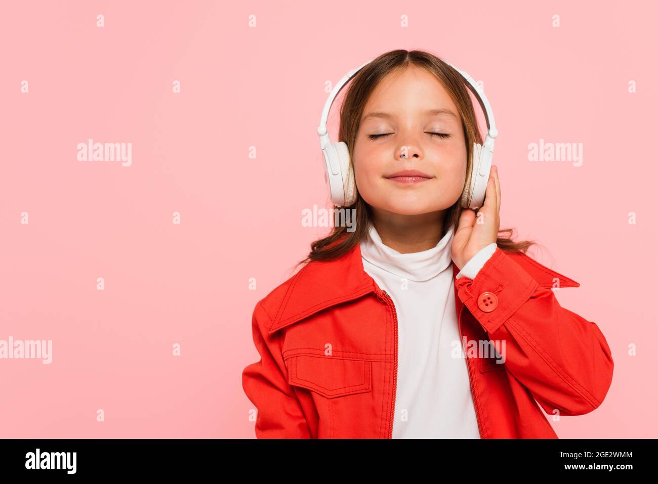 pleased child in orange jacket listening music with closed eyes ...