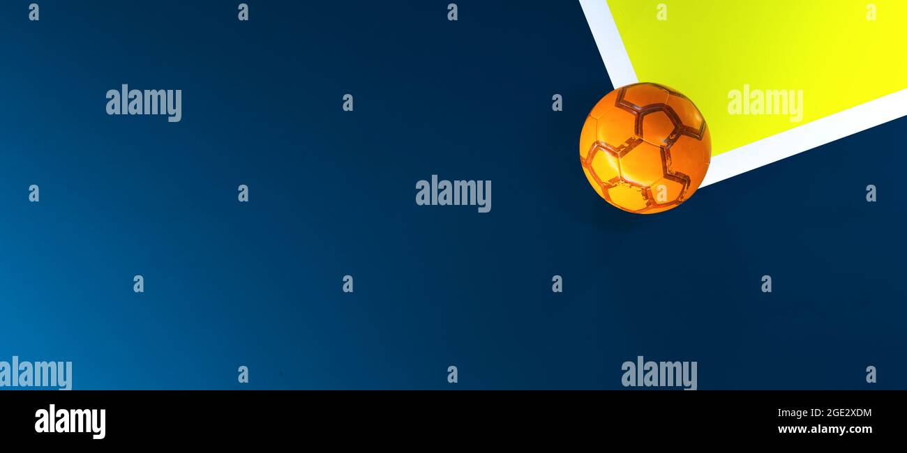 Orange futsal soccer ball in the corner of a blue, yellow indoor field ...