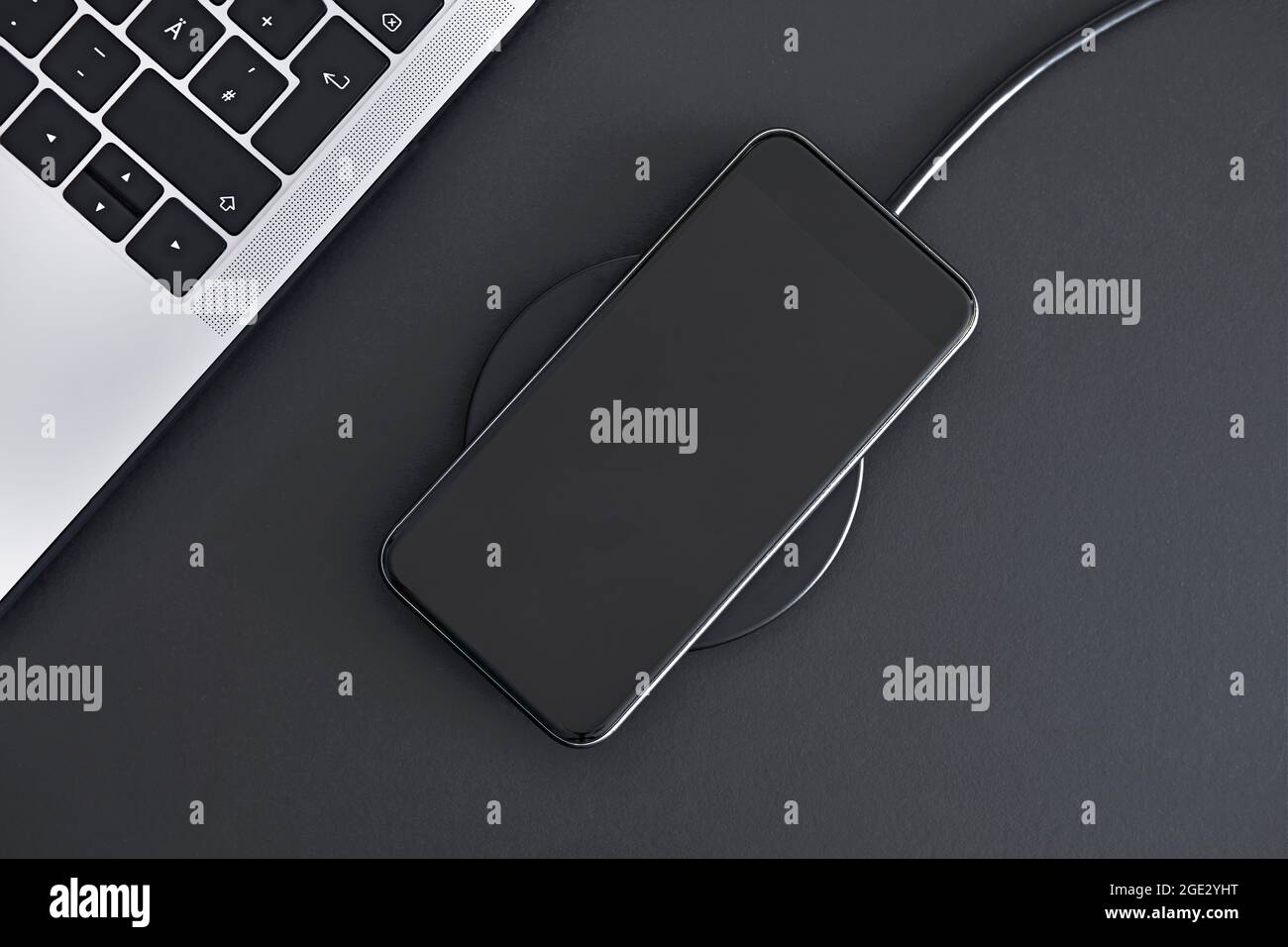 Wireless charging of smartphone. High angle view of laptop and mobile ...