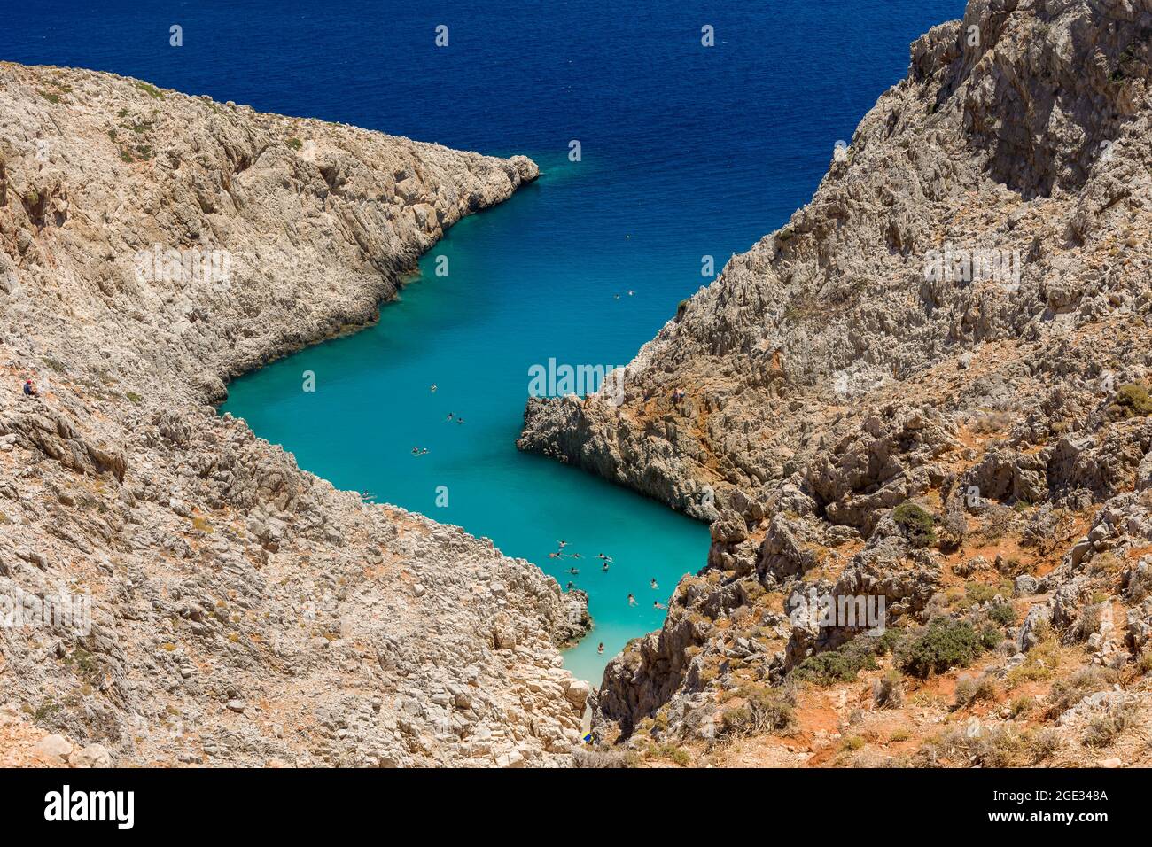 Small sandy beach with turquoise ocean hidden between tall cliffs in a ...