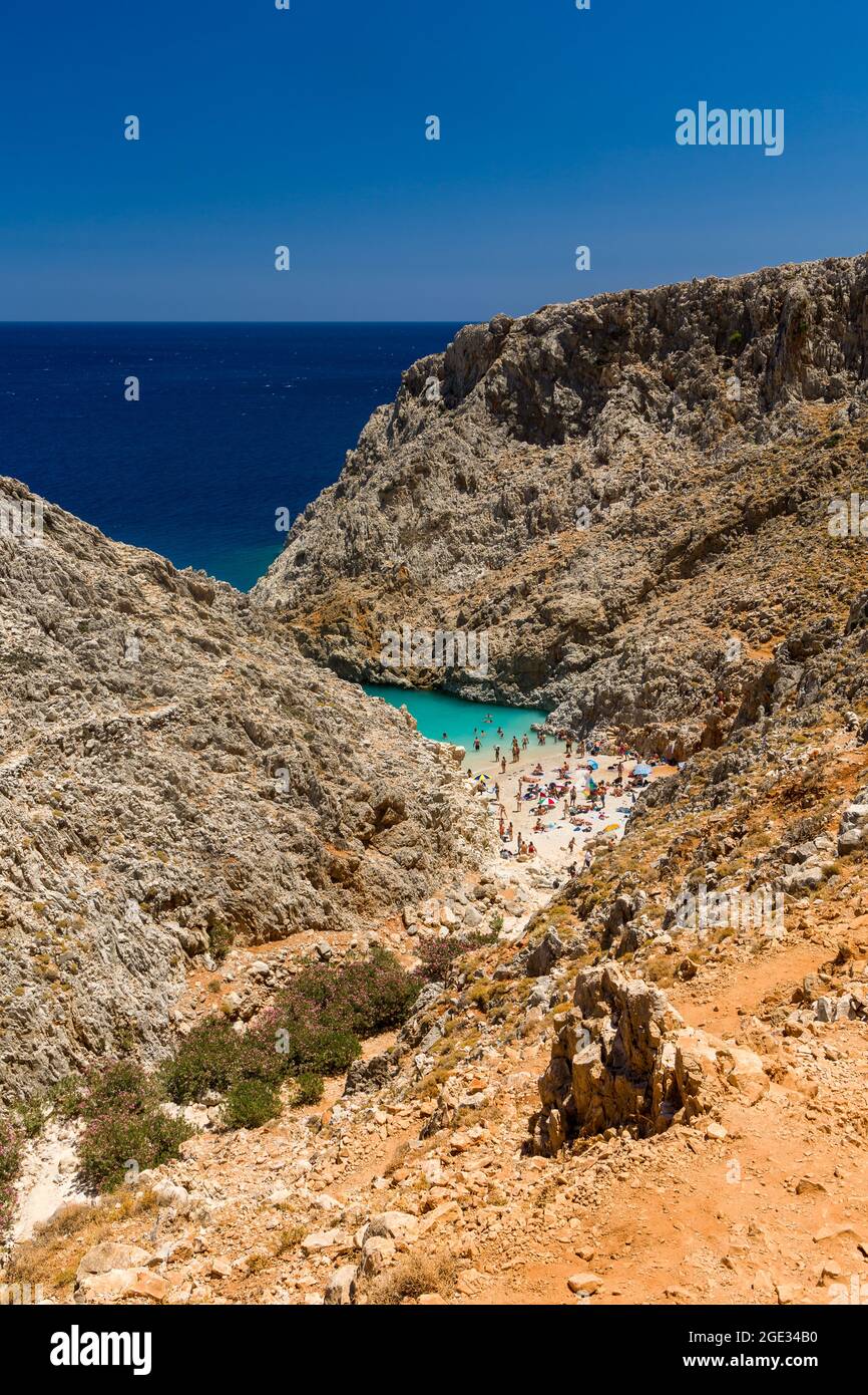 Small sandy beach with turquoise ocean hidden between tall cliffs in a ...