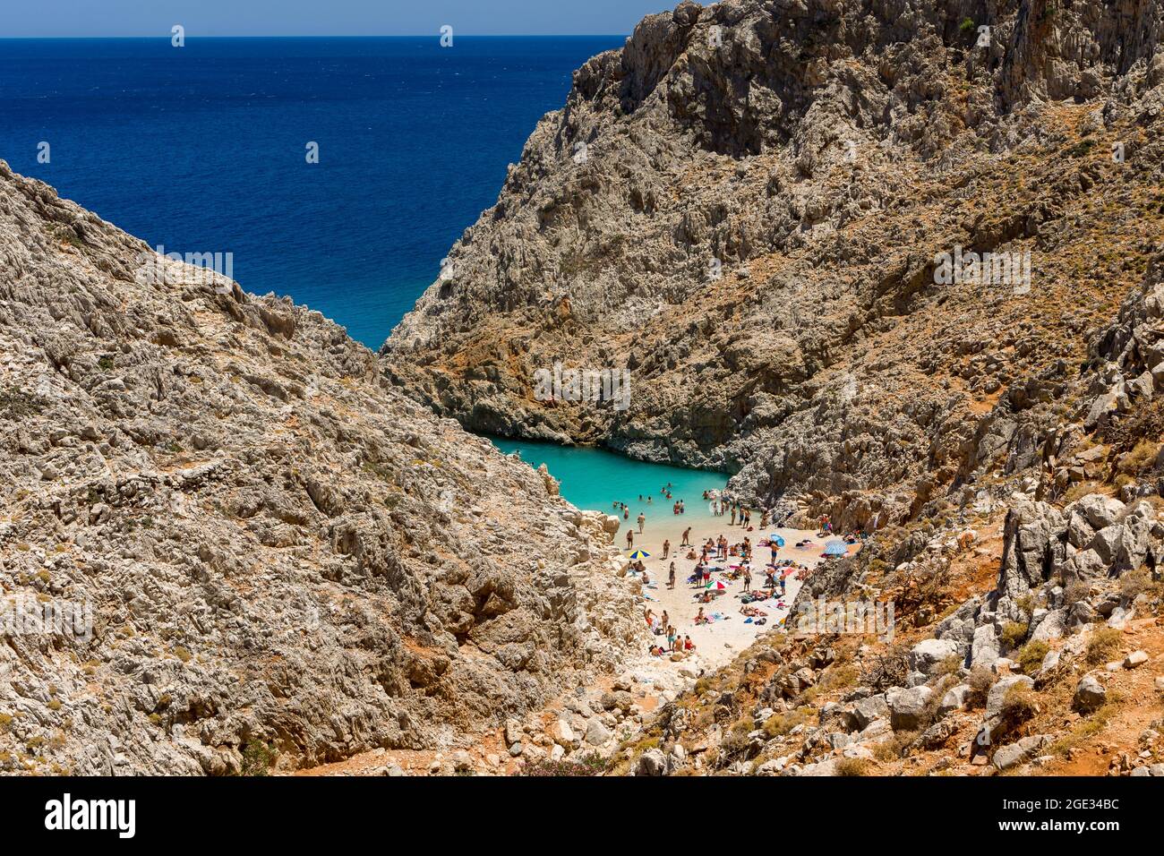 Small sandy beach with turquoise ocean hidden between tall cliffs in a ...